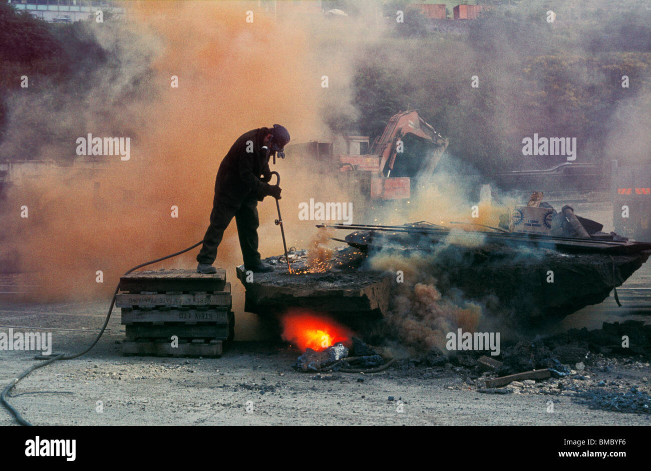 Man using a thermal lance to cut up slag waste from a steel furnace ...