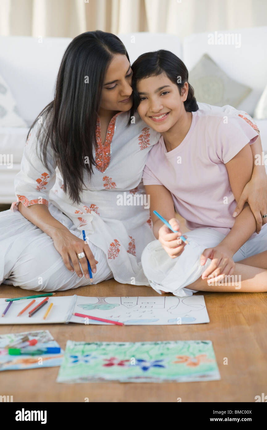Girl making a drawing with her mother sitting beside her Stock Photo ...