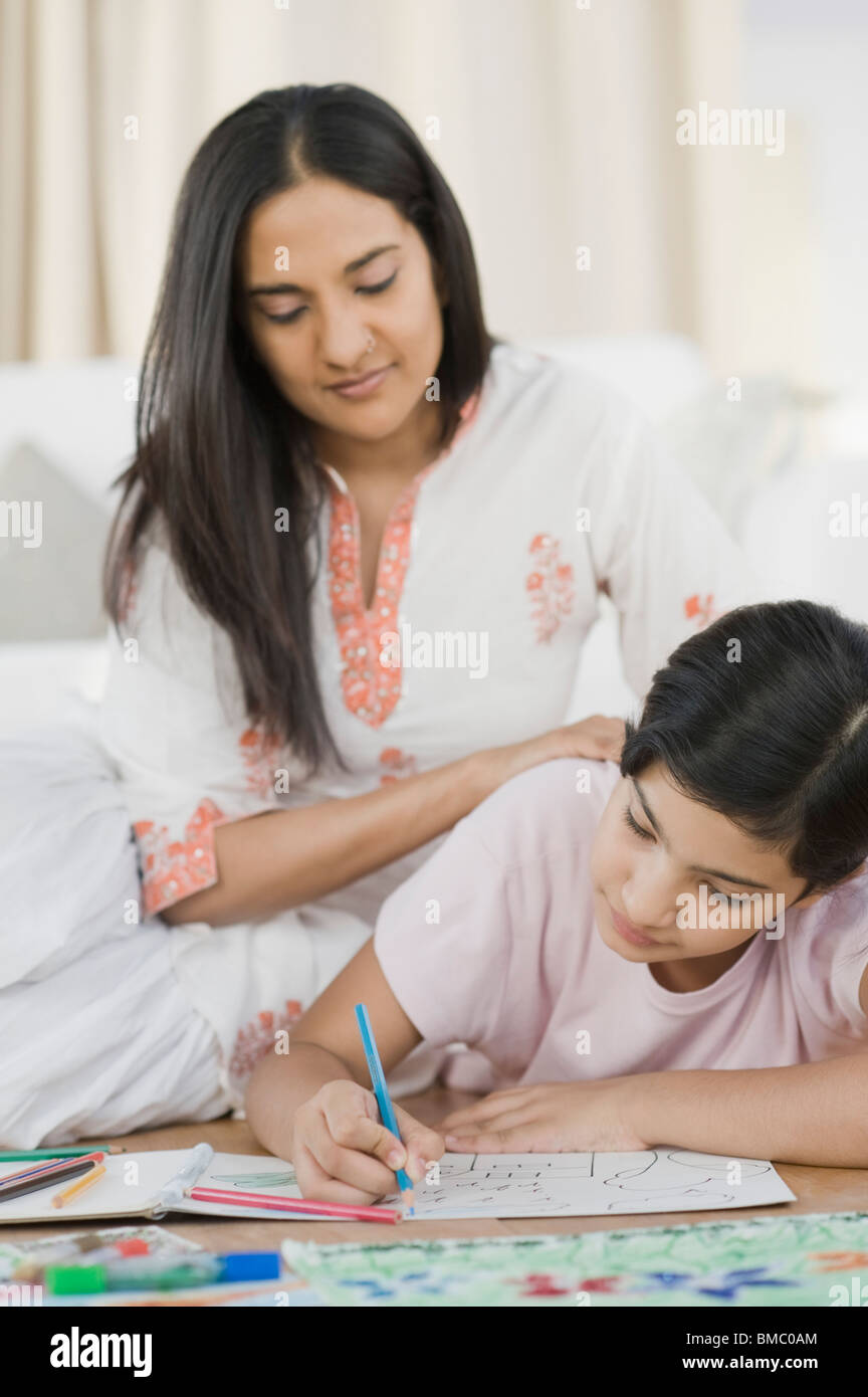 Girl making a drawing with her mother sitting beside her Stock Photo ...