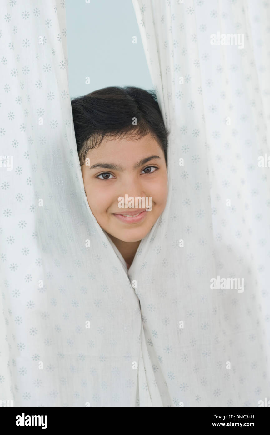 Portrait of a girl smiling behind curtains Stock Photo - Alamy
