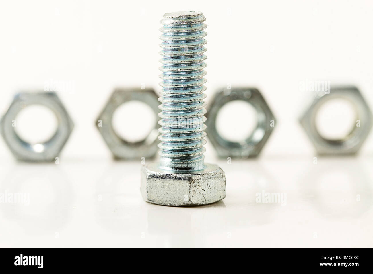 one screw standing in front of four bolts on white background Stock ...