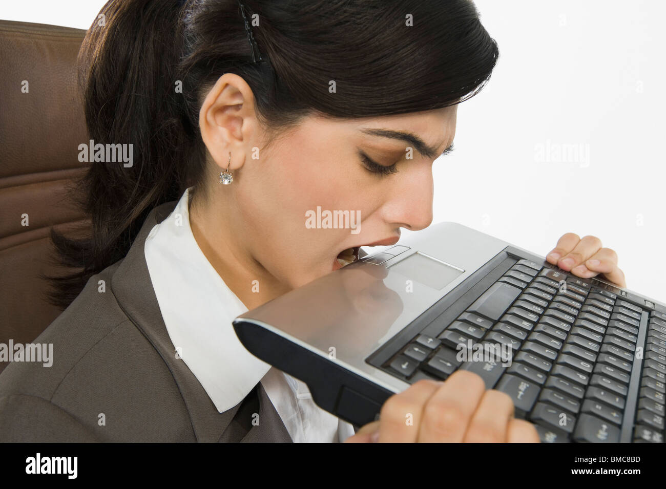Businesswoman biting a laptop Stock Photo - Alamy