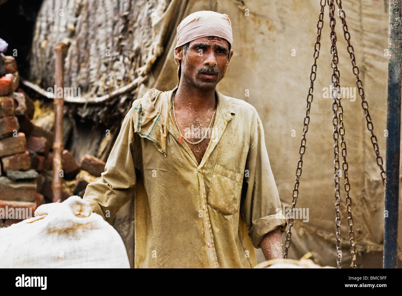 Man holding straw sacks for weighing in a straw store, Delhi, India ...
