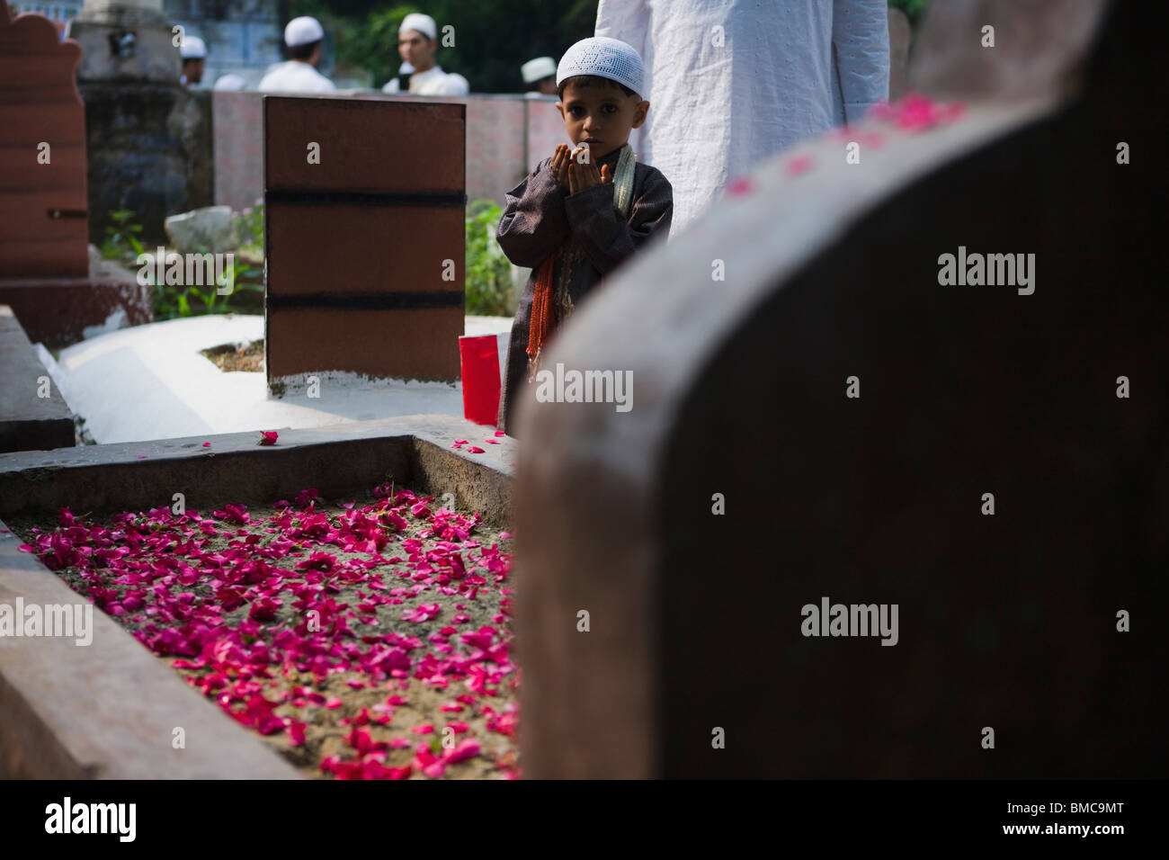 Boy praying with his father at a grave in a cemetery, Old Delhi, India ...