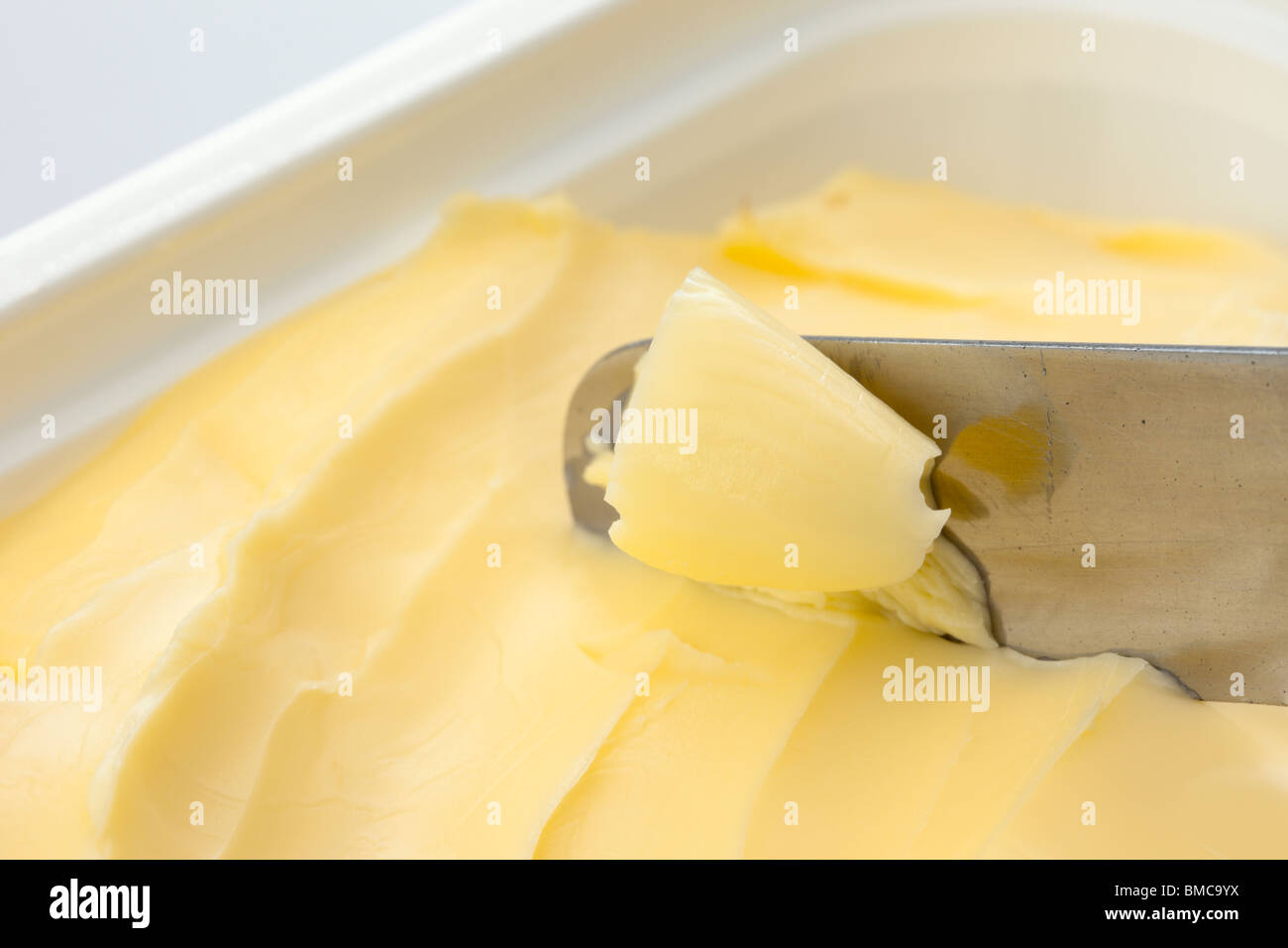 Knife scooping up spreadable dairy spread in a tub Stock Photo - Alamy