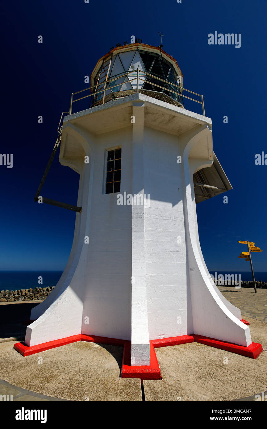 Upward view of a white lighthouse with a red base, situated near an ...