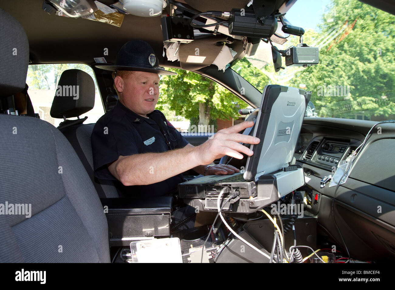 Nebraska State Trooper using laptop computer in cruiser to read output ...