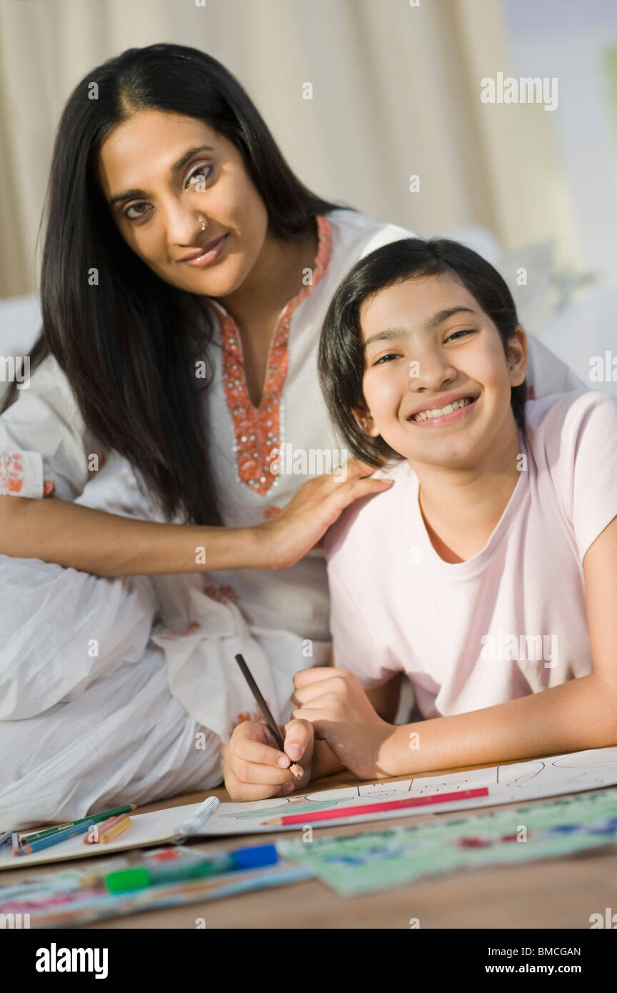 Girl making a drawing with her mother sitting beside her Stock Photo ...