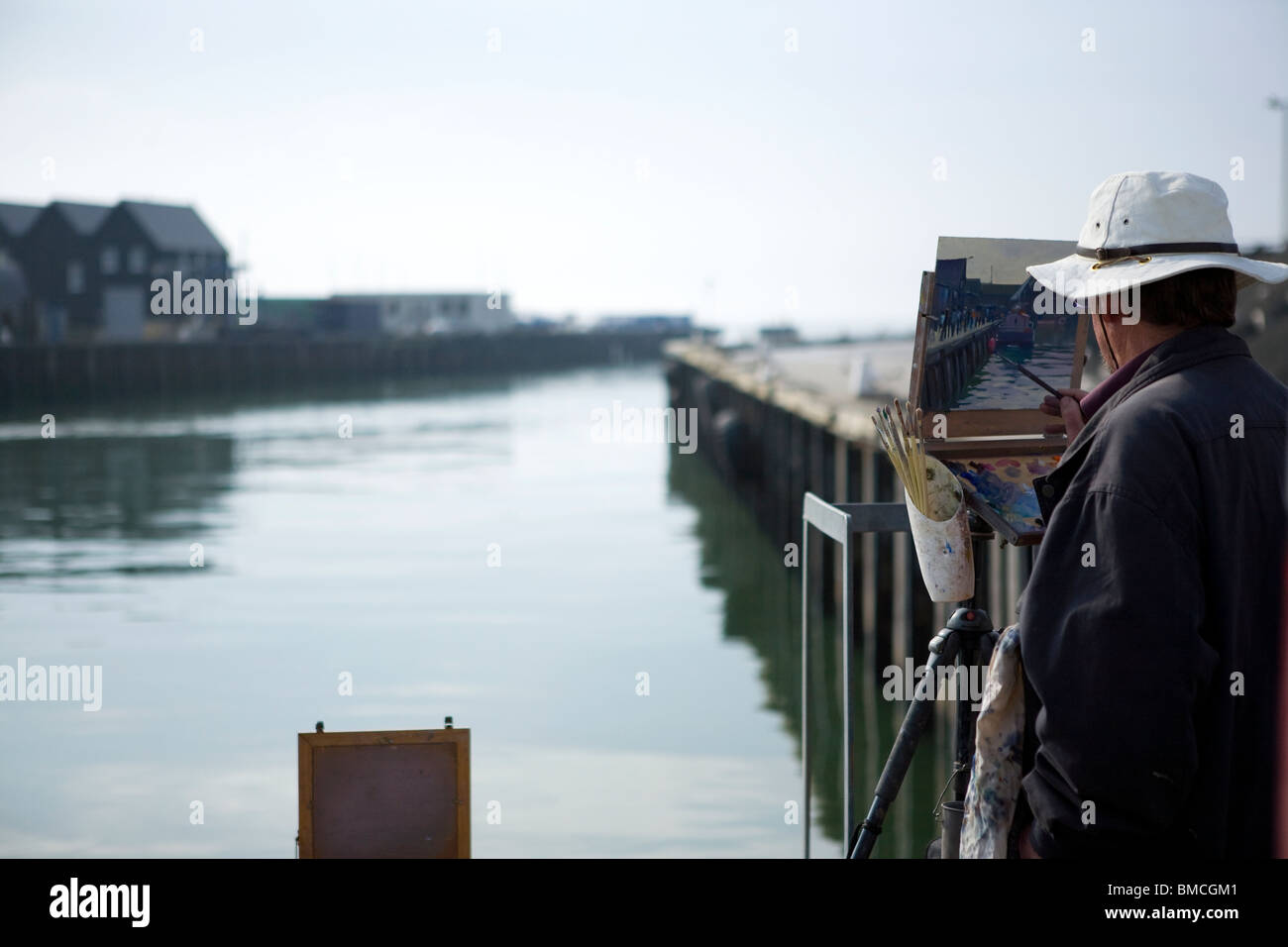 Artist painting landscape of Whitstable harbour showing the reflection ...