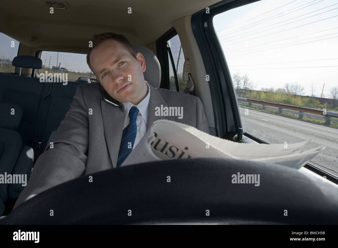 Driver Talking on Cell Phone and Reading Newspaper Stock Photo - Alamy