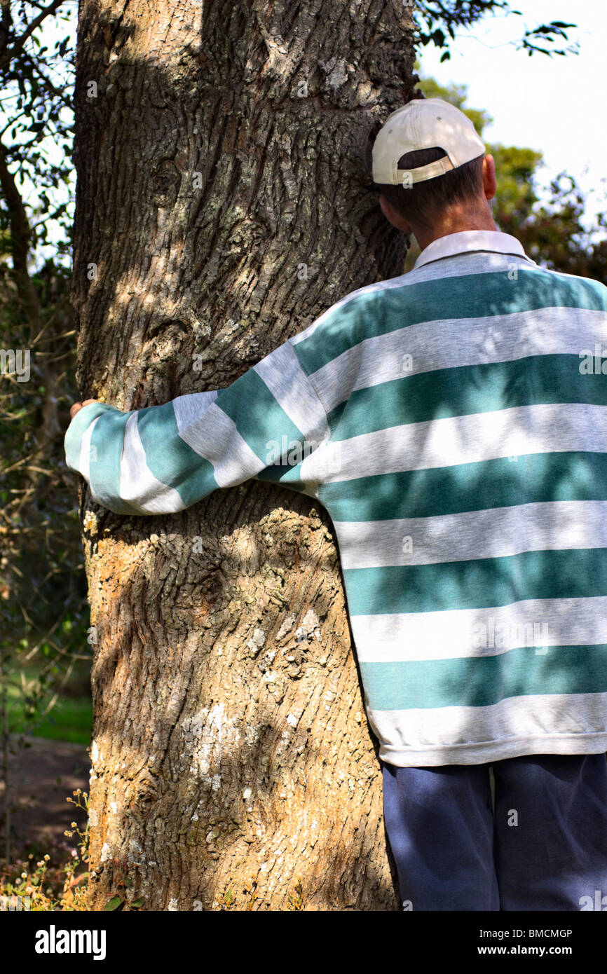 Mature man hugging a tree Stock Photo - Alamy