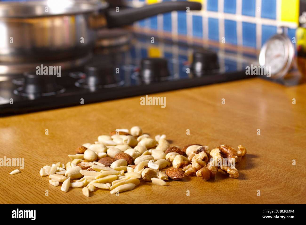 Assorted nuts on kitchen counter-top beside stove. Foreground focus ...