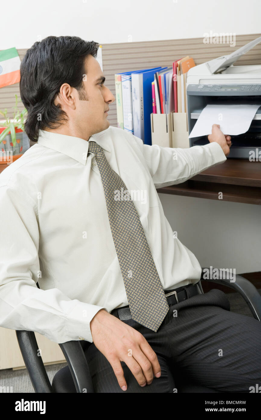 Businessman taking a printout on a printer Stock Photo - Alamy
