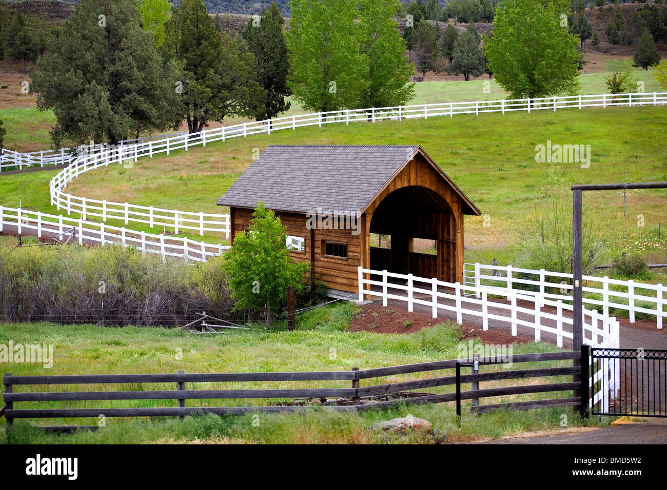 A white rail fence and small covered bridge in eastern Oregon near the ...