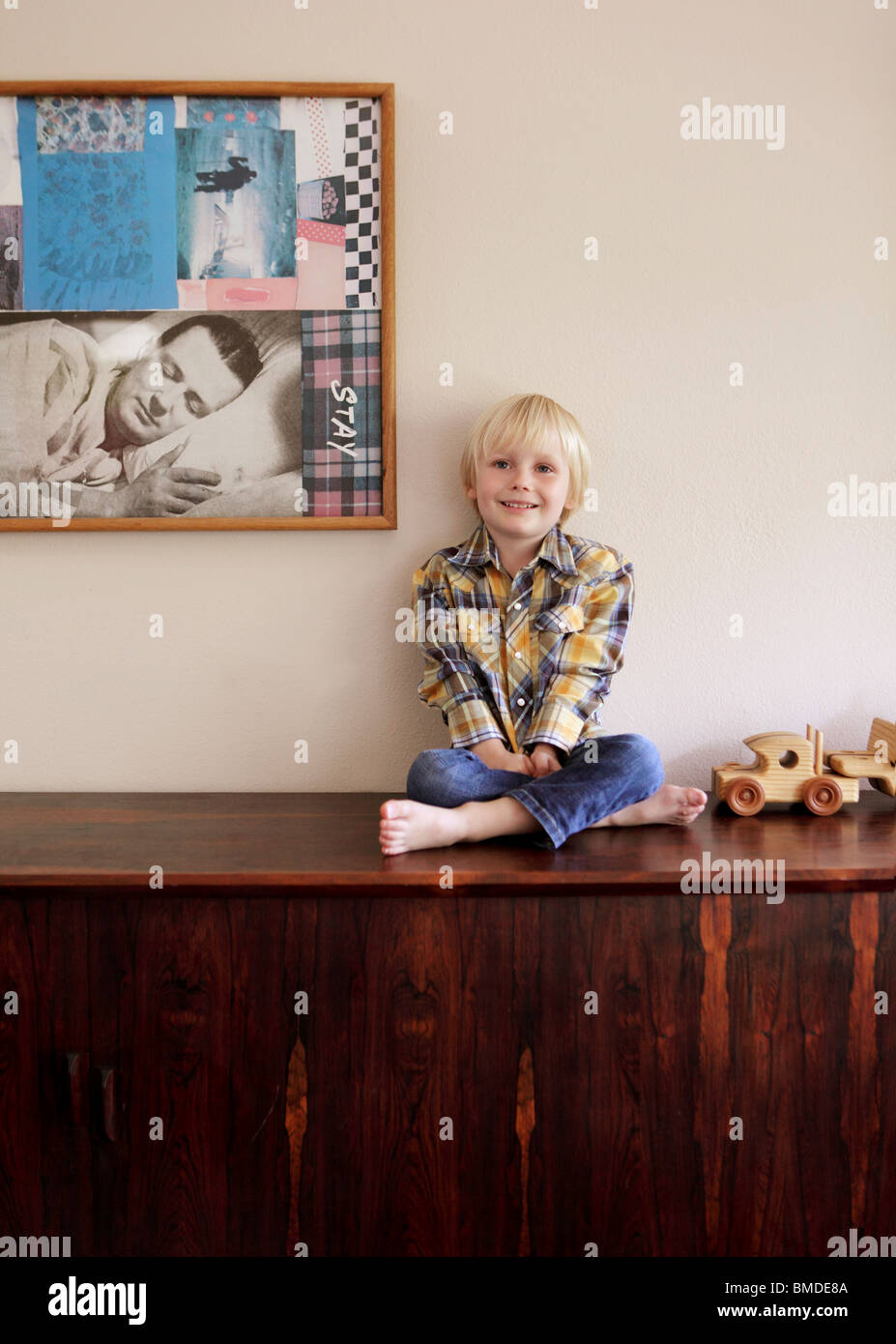 Young boy sitting on shelf Stock Photo - Alamy