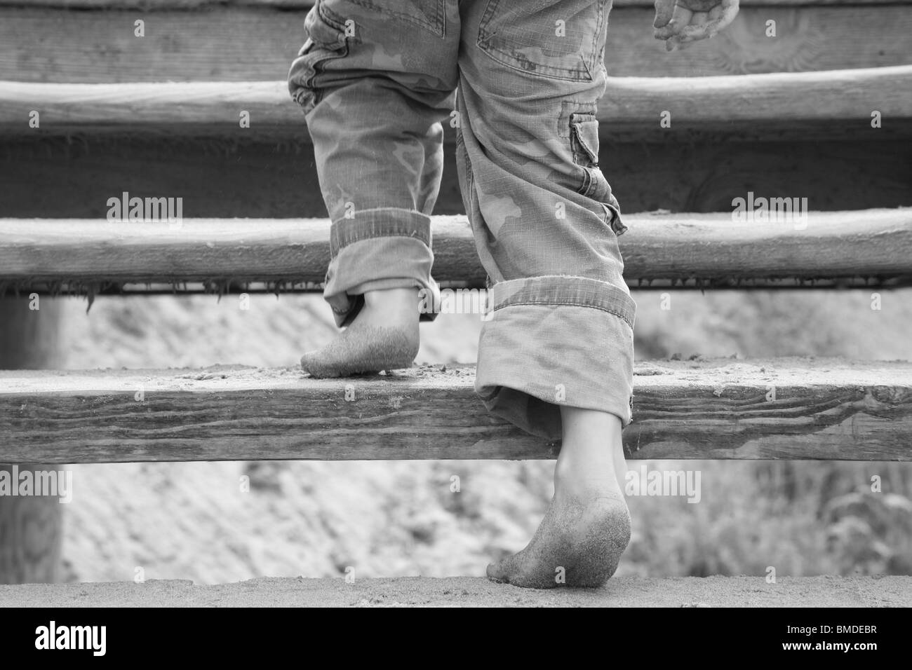 Young boy with sandy feet going up wooden stairs Stock Photo - Alamy