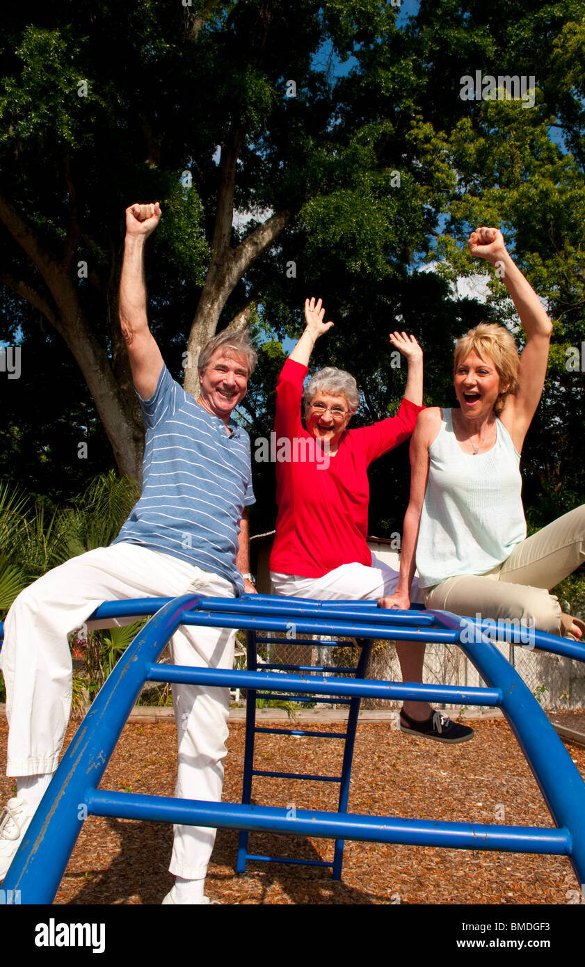 Retired senior freinds relaxing and having fun on monkey bars in park ...