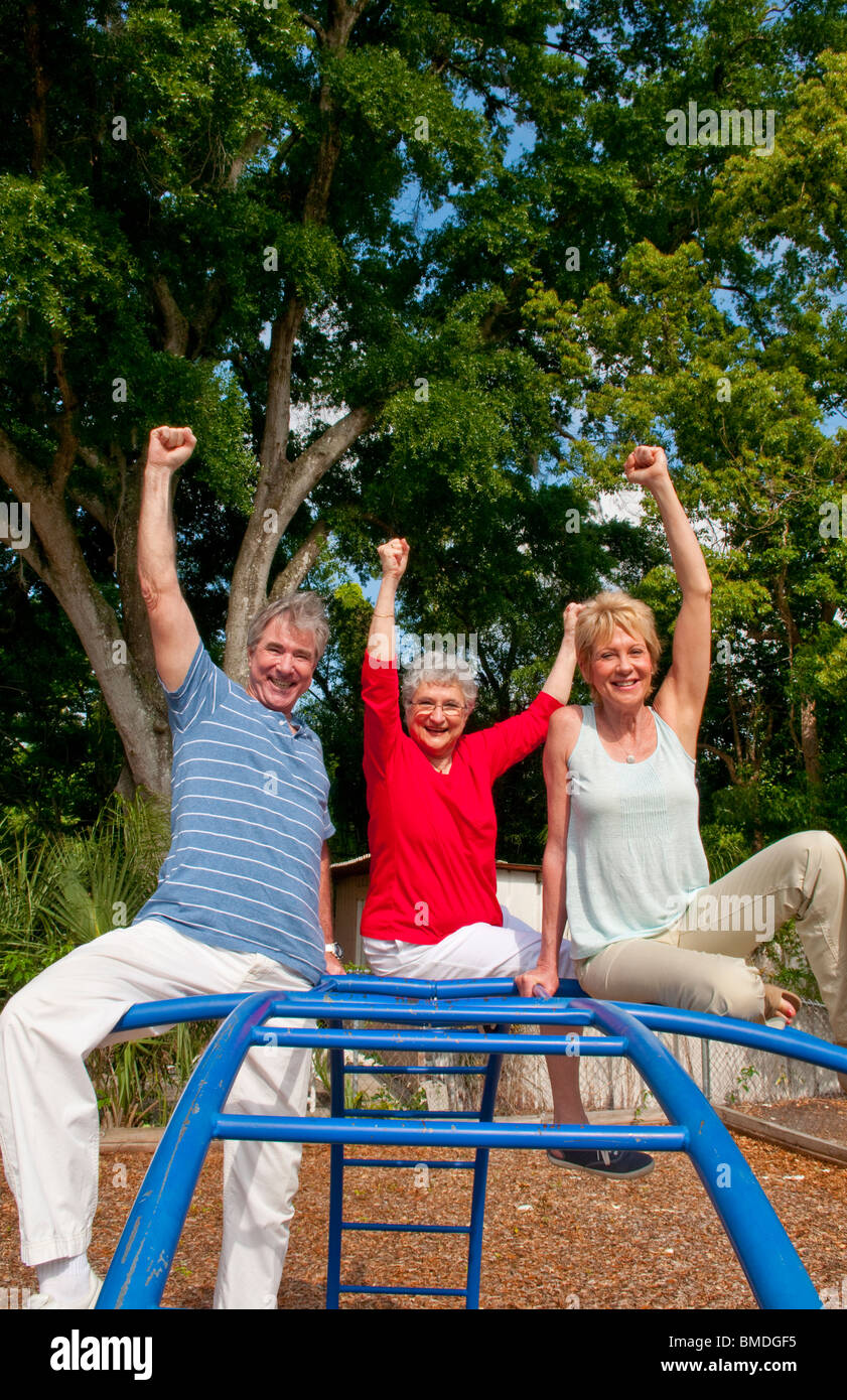 Retired senior freinds relaxing and having fun on monkey bars in park ...