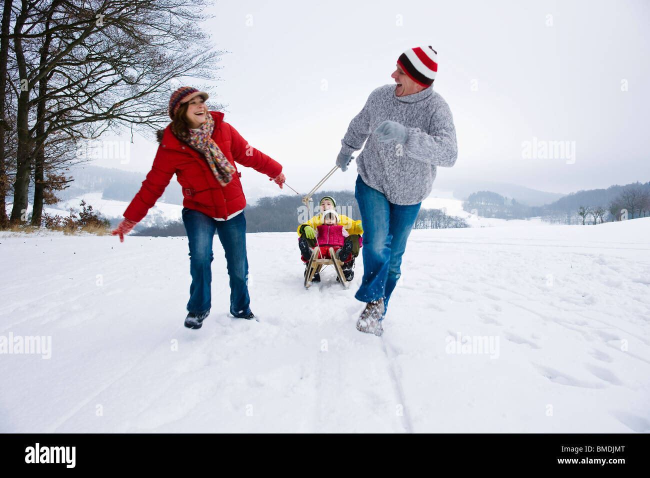 Parents Pulling Children in Sled in Winter Stock Photo - Alamy