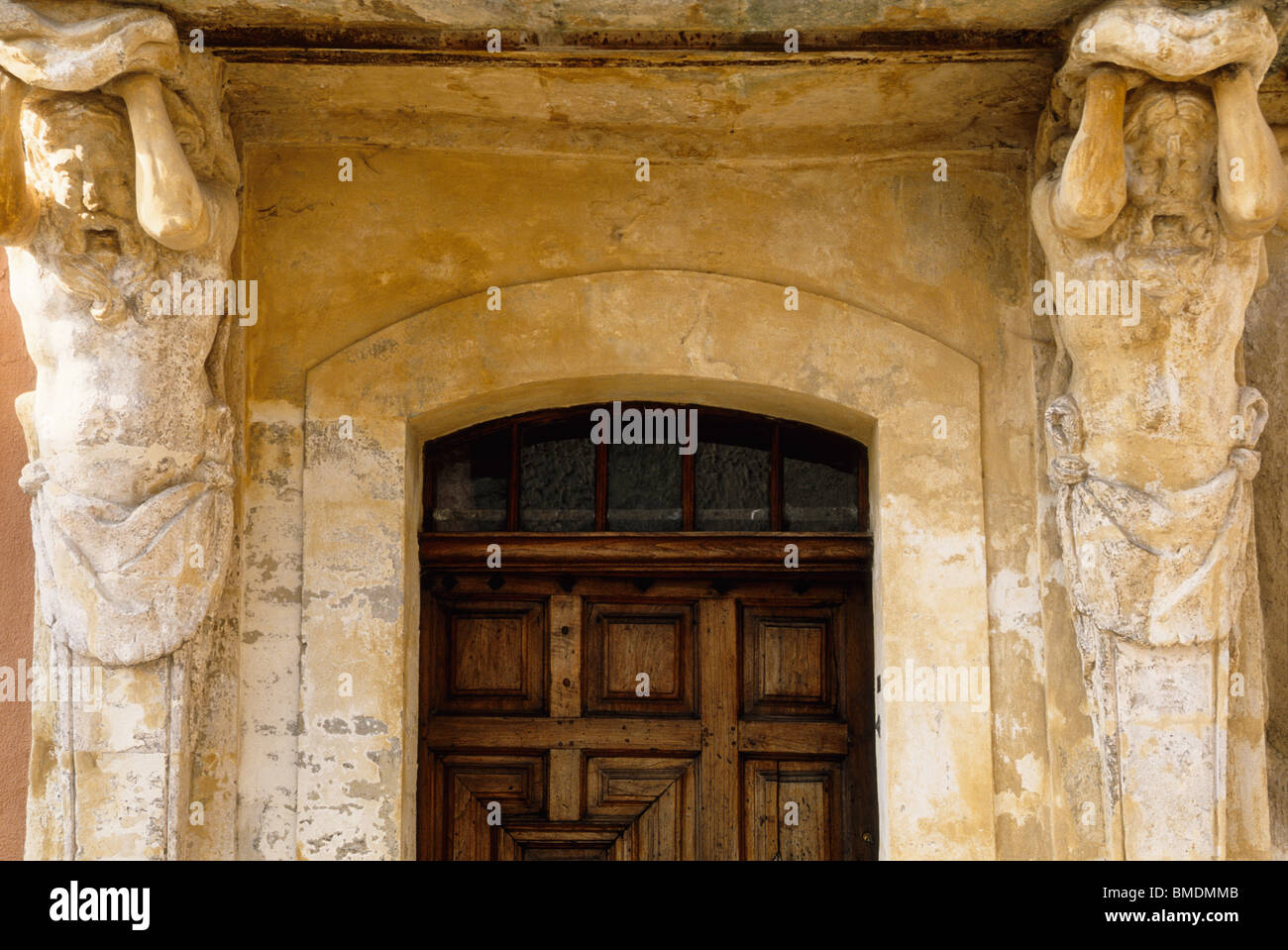 Wooden door between two statue representing two men supporting a ...