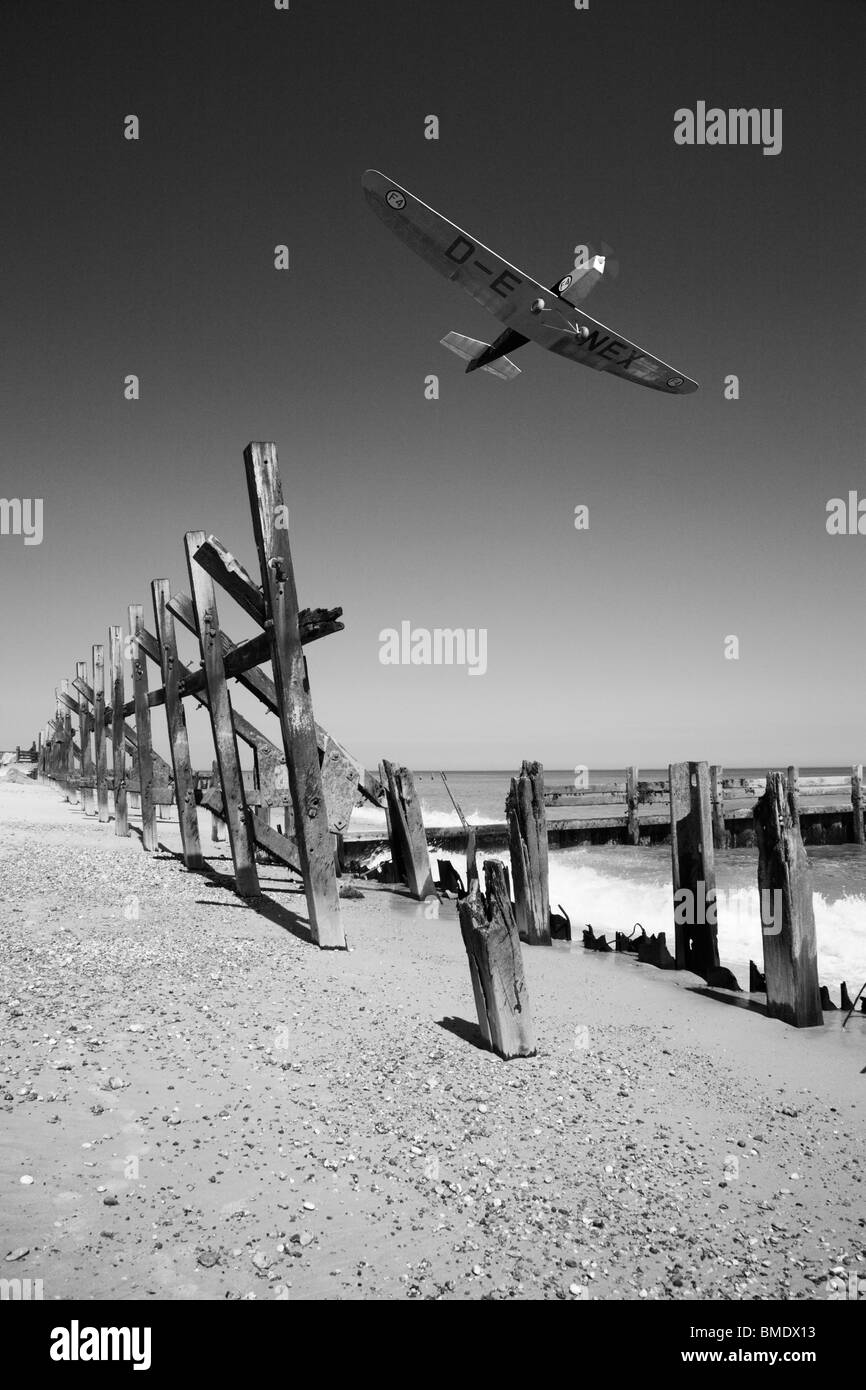 An old small aircraft flying over broken sea defenses Stock Photo - Alamy