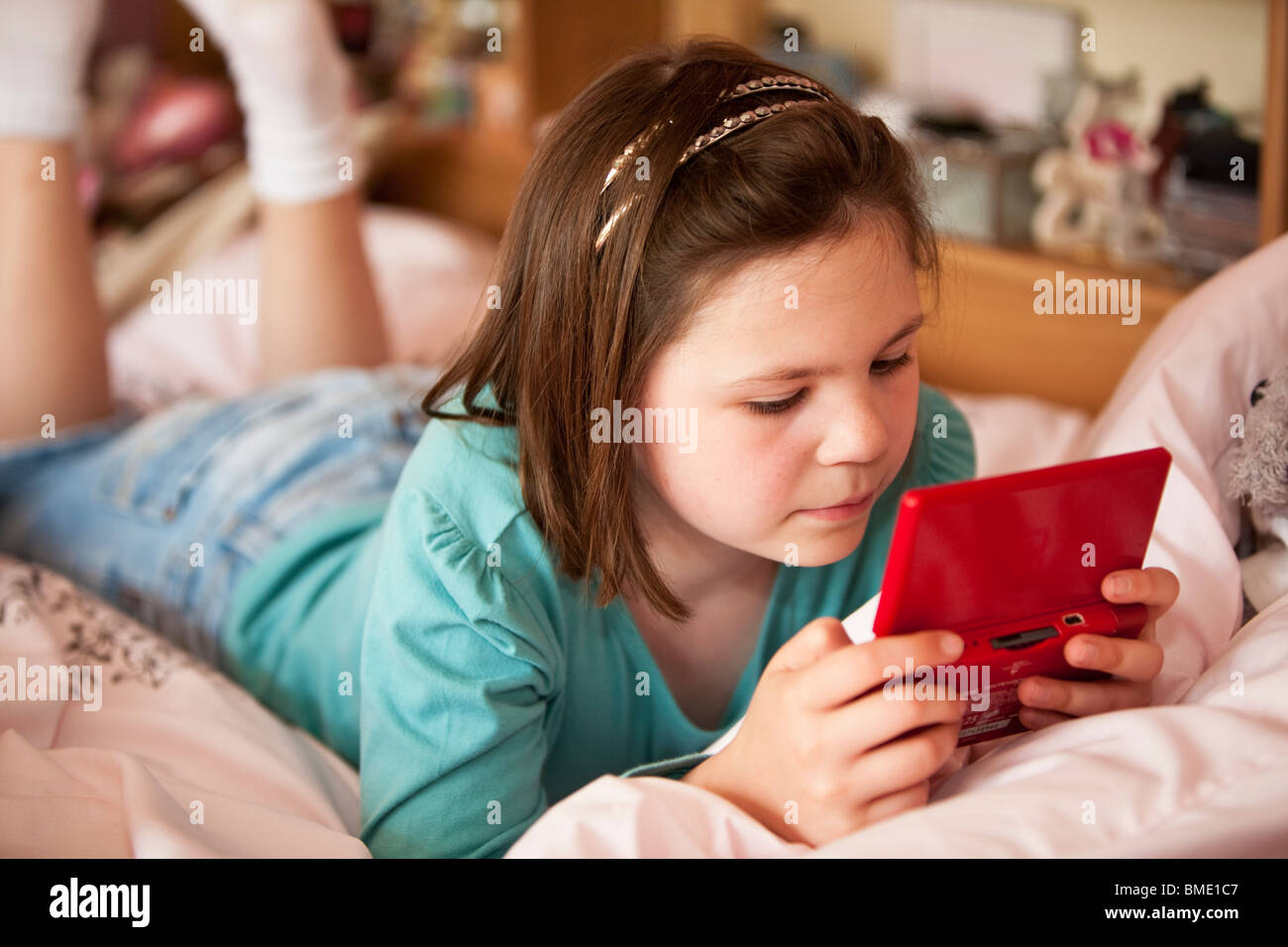 Young girl playing on a Nintendo DS computer game on her bed Stock ...