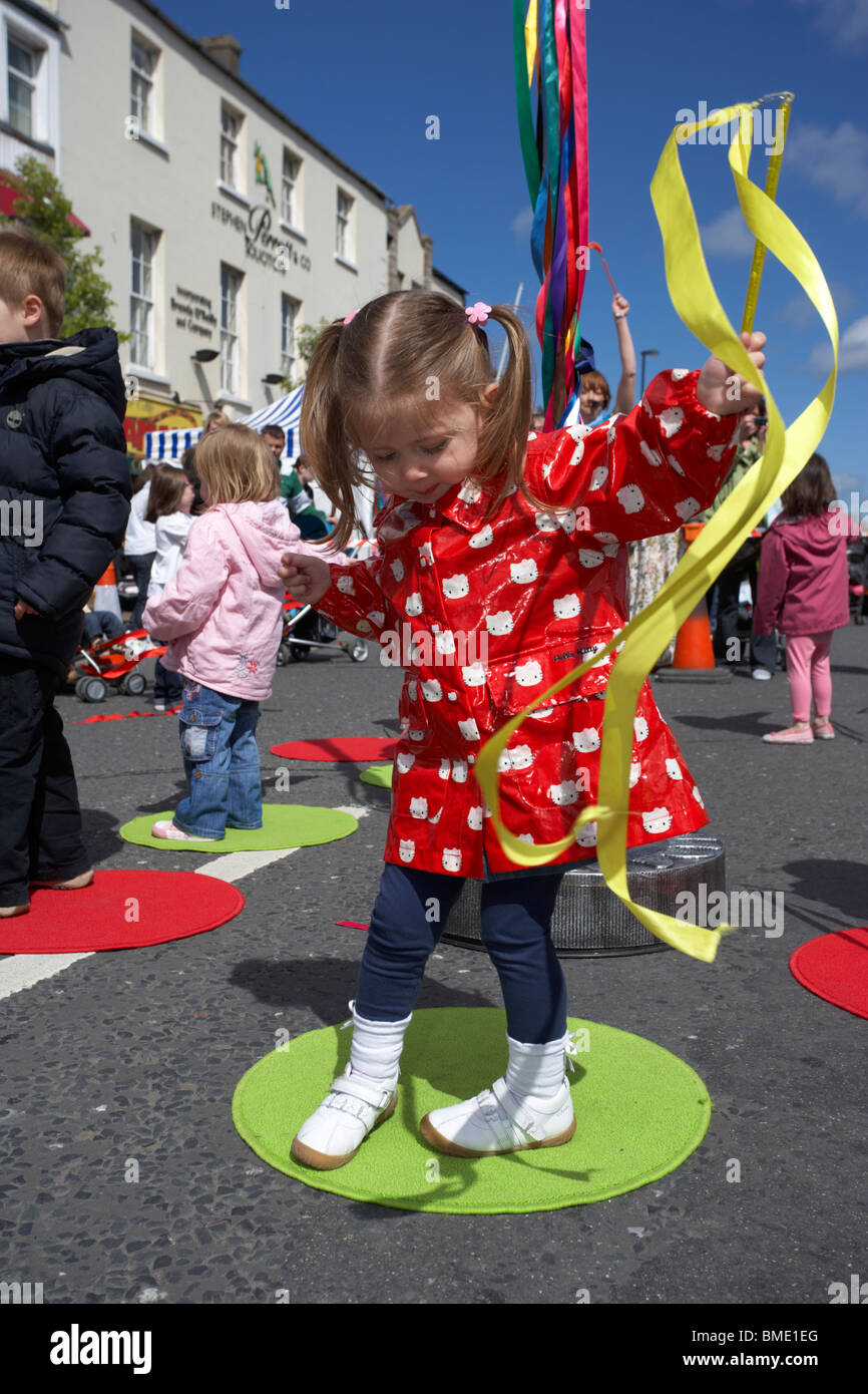 young girl dancing with ribbon around a mini maypole on may day in ...