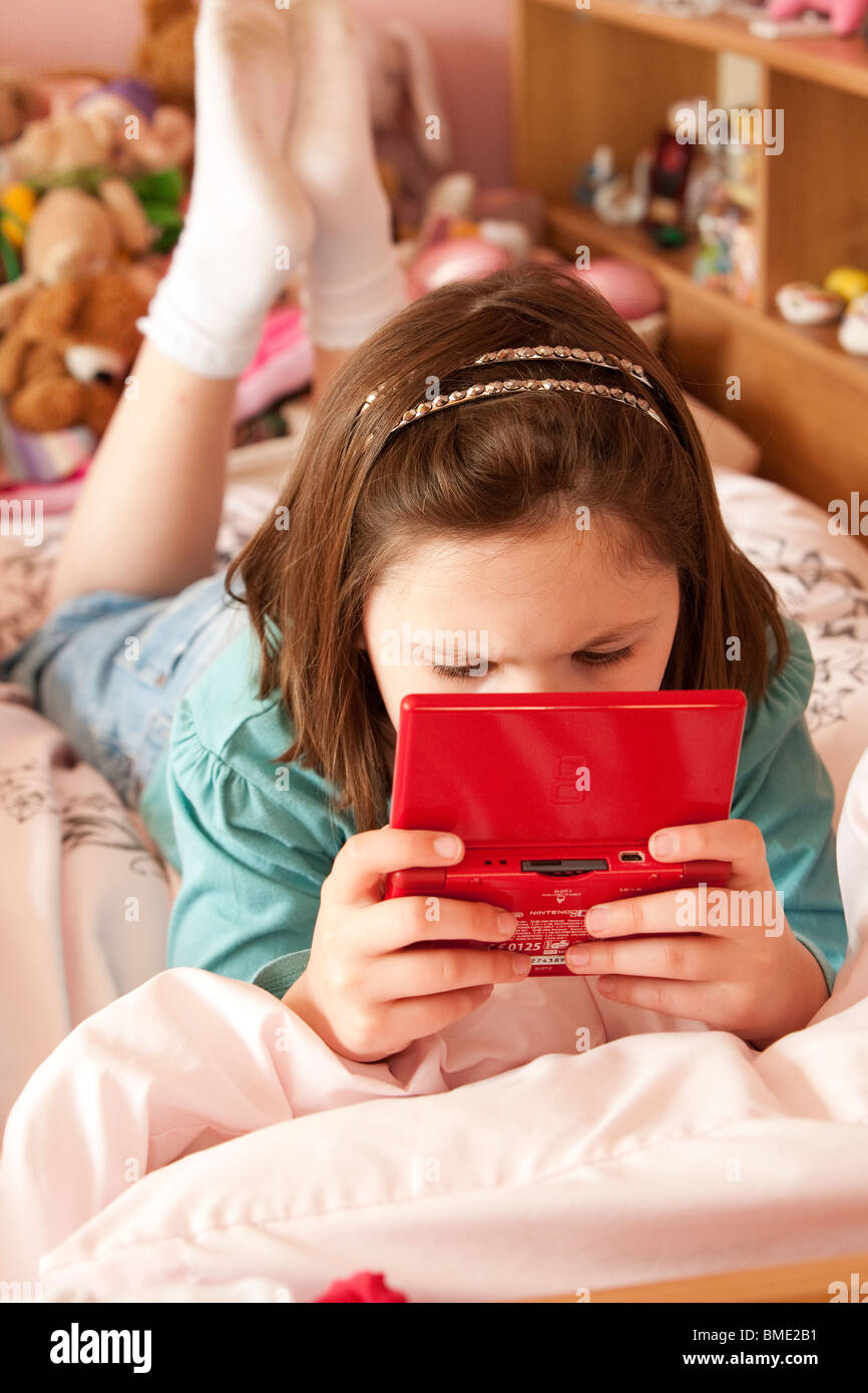 Young girl playing on a Nintendo DS computer game on her bed Stock ...