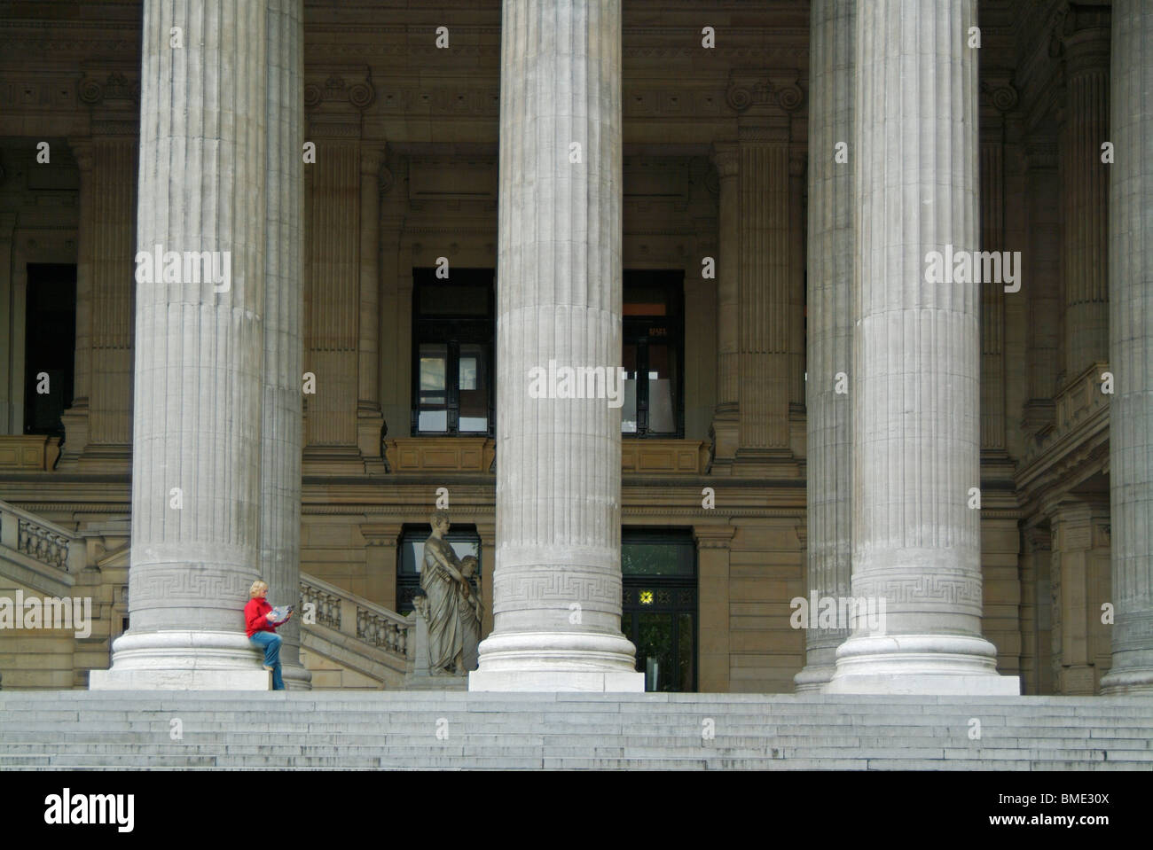 Woman leaning against the stone columns of the Palais de Justice law courts in Brussels Belgium ...