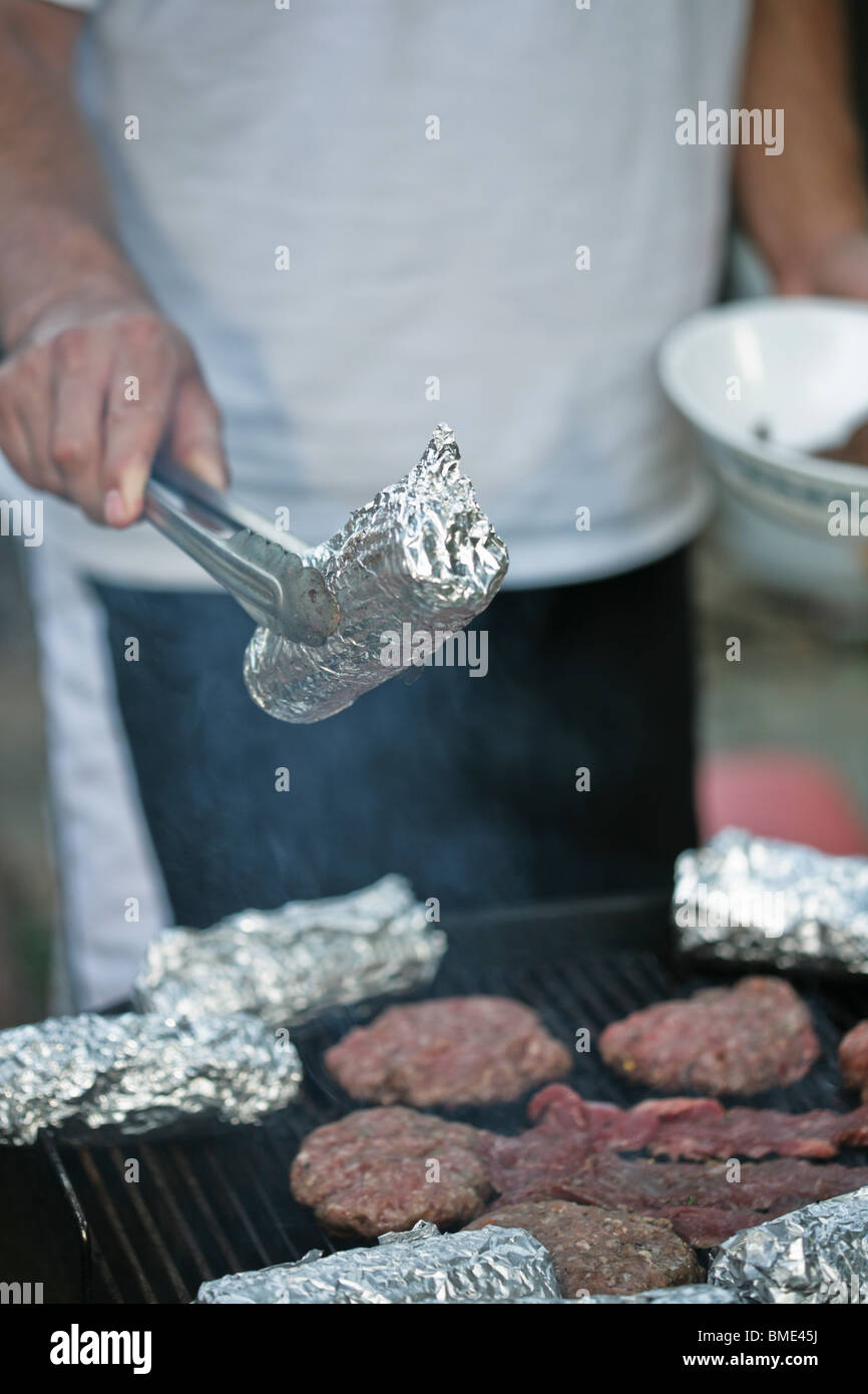 Man tending and removing various meats on a barbecue grill Stock Photo ...