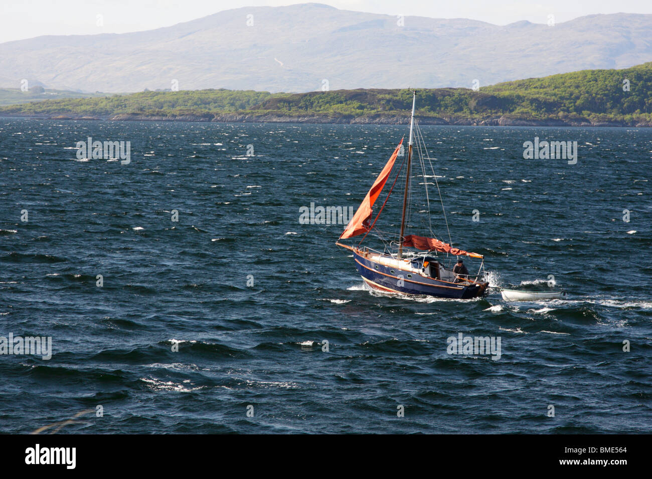 Blue cutter-rigged sailing boat with red sails in choppy sea Stock ...