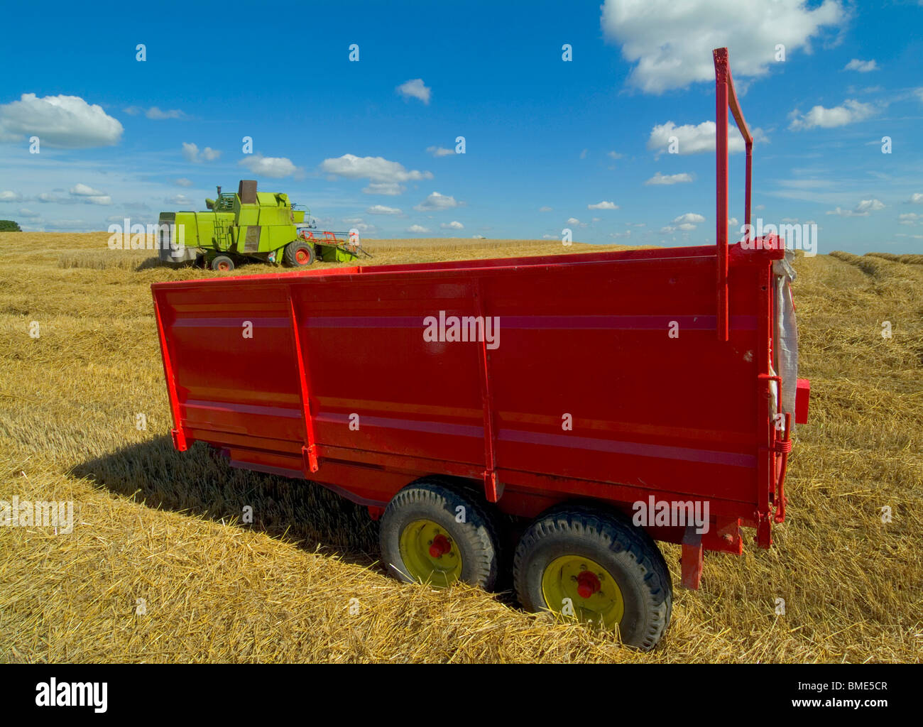 Large green combine harvester and red storage wagon during harvest ...