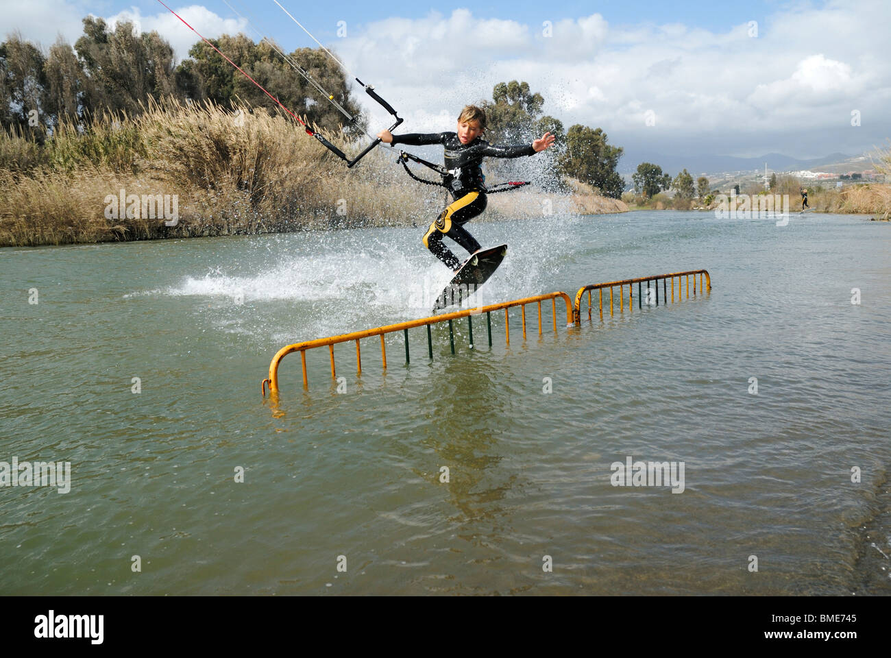 Young kite surfer jumping out of the water and onto sunken steel ...