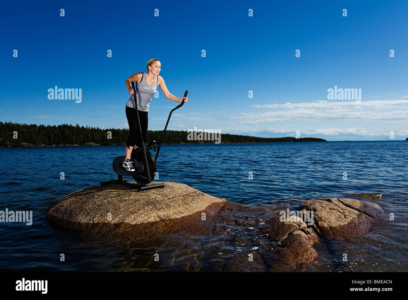 Young woman on a working out on a rock in a lake, Sweden Stock Photo ...