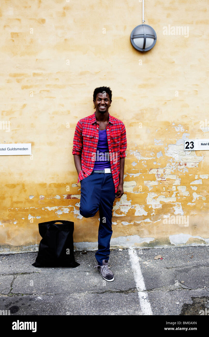 Man leaning on one leg near wall Stock Photo - Alamy