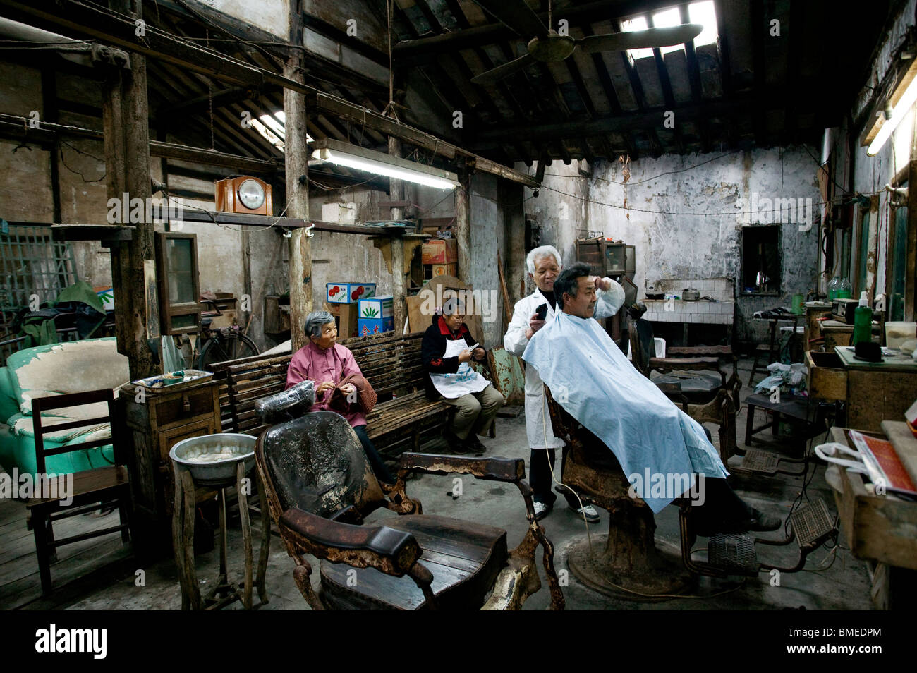 Elderly barber giving his client a haircut in a traditional barbershop ...