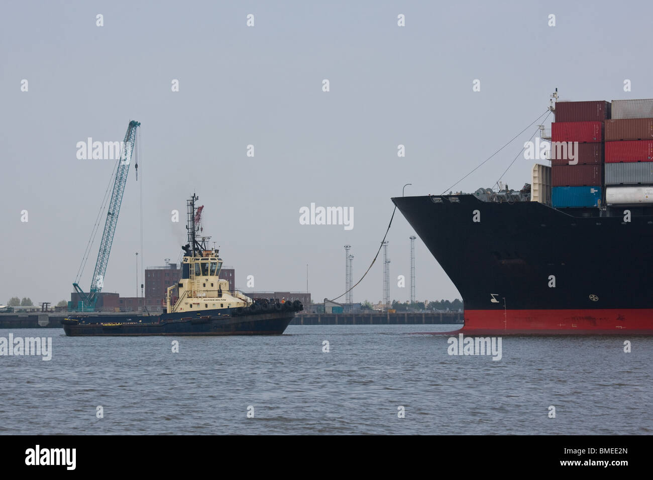 Tug towing a container ship into harbour Stock Photo - Alamy