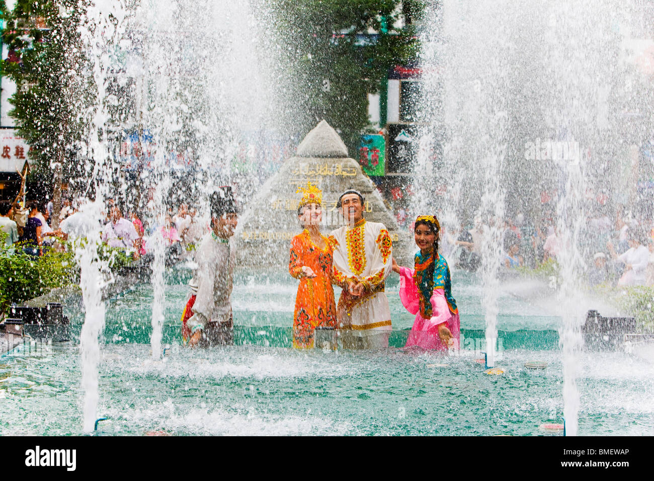 Uygur people in traditional costume standing in fountain, International ...