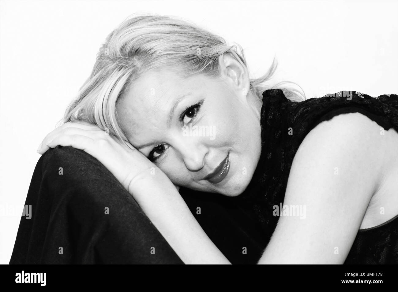 portrait of beautiful blond woman on sofa leaning over and smiling at ...