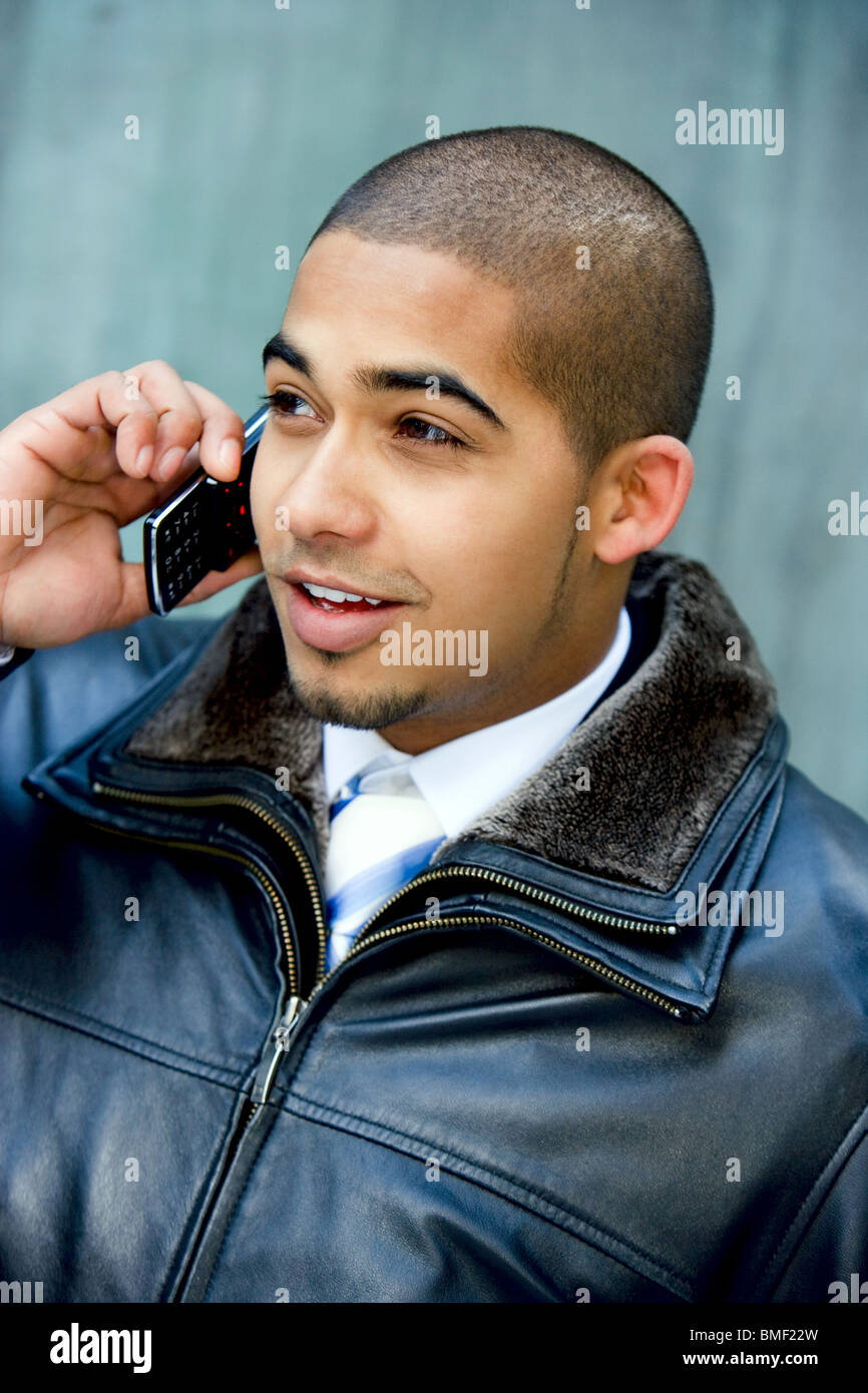 Young urban professional in his early 20's speaking on a cell phone ...