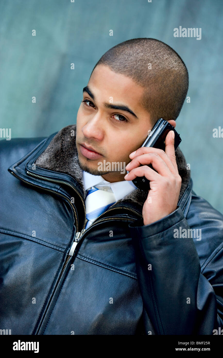 Young urban professional in his early 20's speaking on a cell phone ...