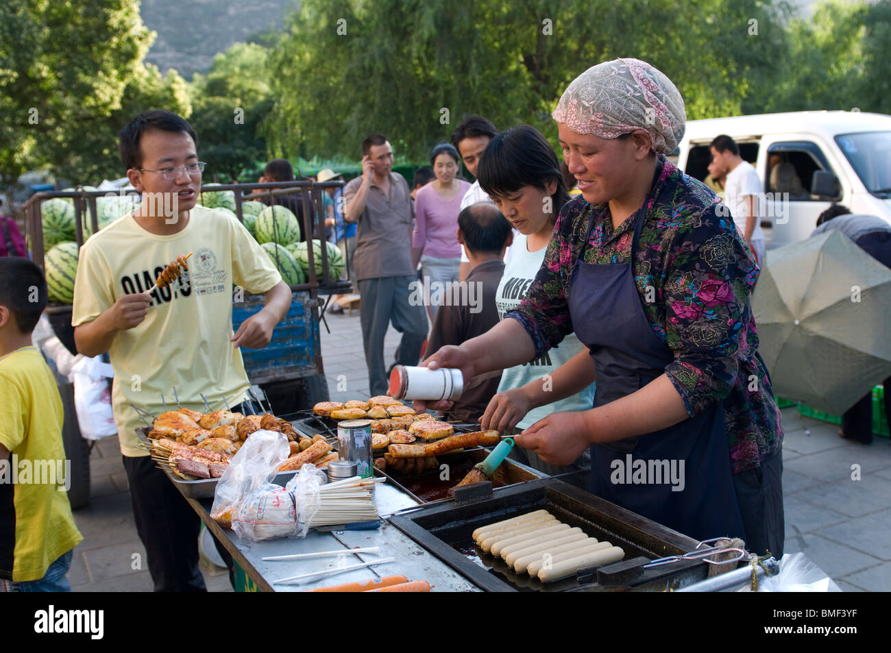 Woman frying sausages in a food stall, Lanzhou, Gansu Province, China ...