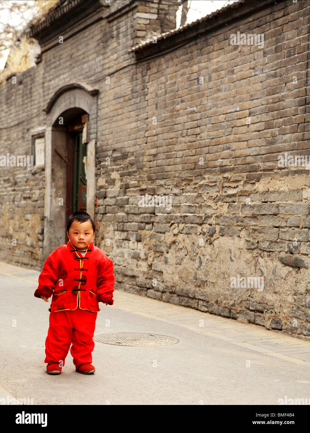 Chinese boy in red traditional costume looking at camera, Hutong ...
