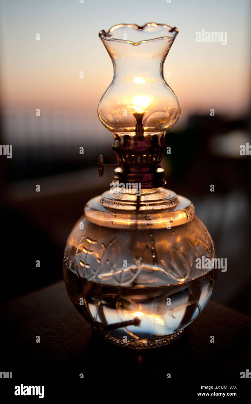 Glass oil lamp on table with sunset appearing as the light source Stock ...