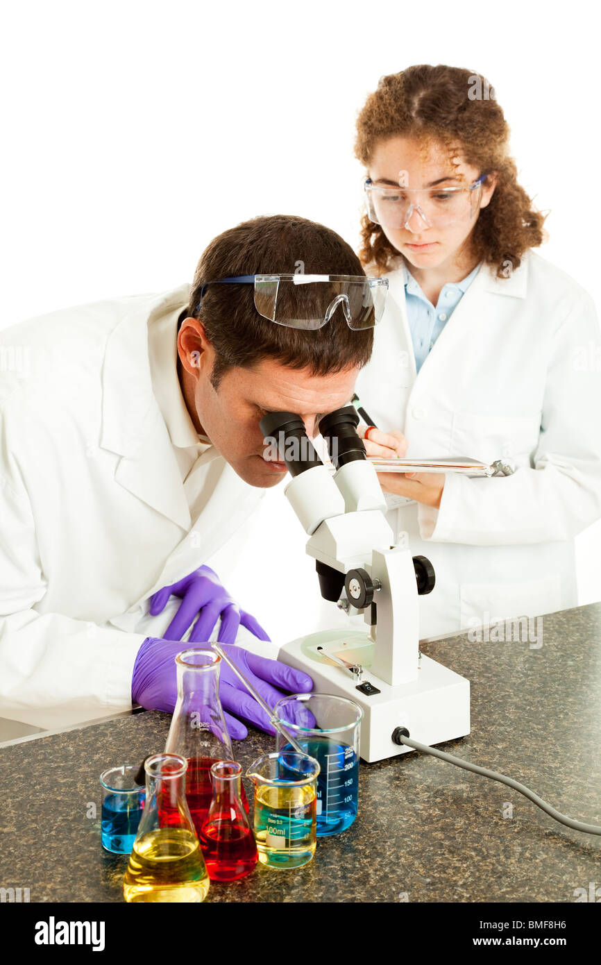 Scientist looking through microscope while his assistant takes notes ...