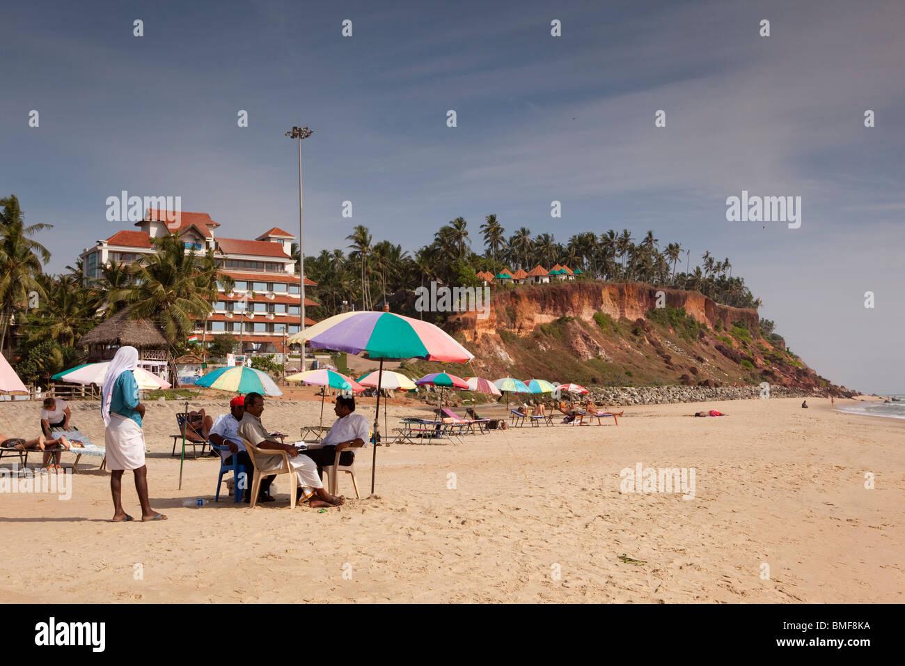 India, Kerala, Varkala beach, Indian lifeguards in shade of parasol ...