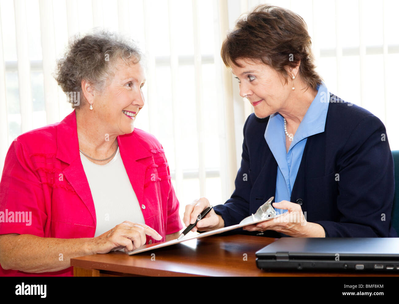 Mature businesswoman discusses a contract with her senior client. Could ...