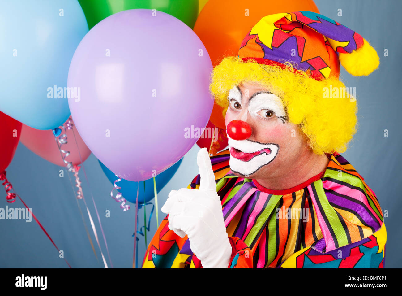 Colorful circus clown making the shhh gesture Stock Photo - Alamy