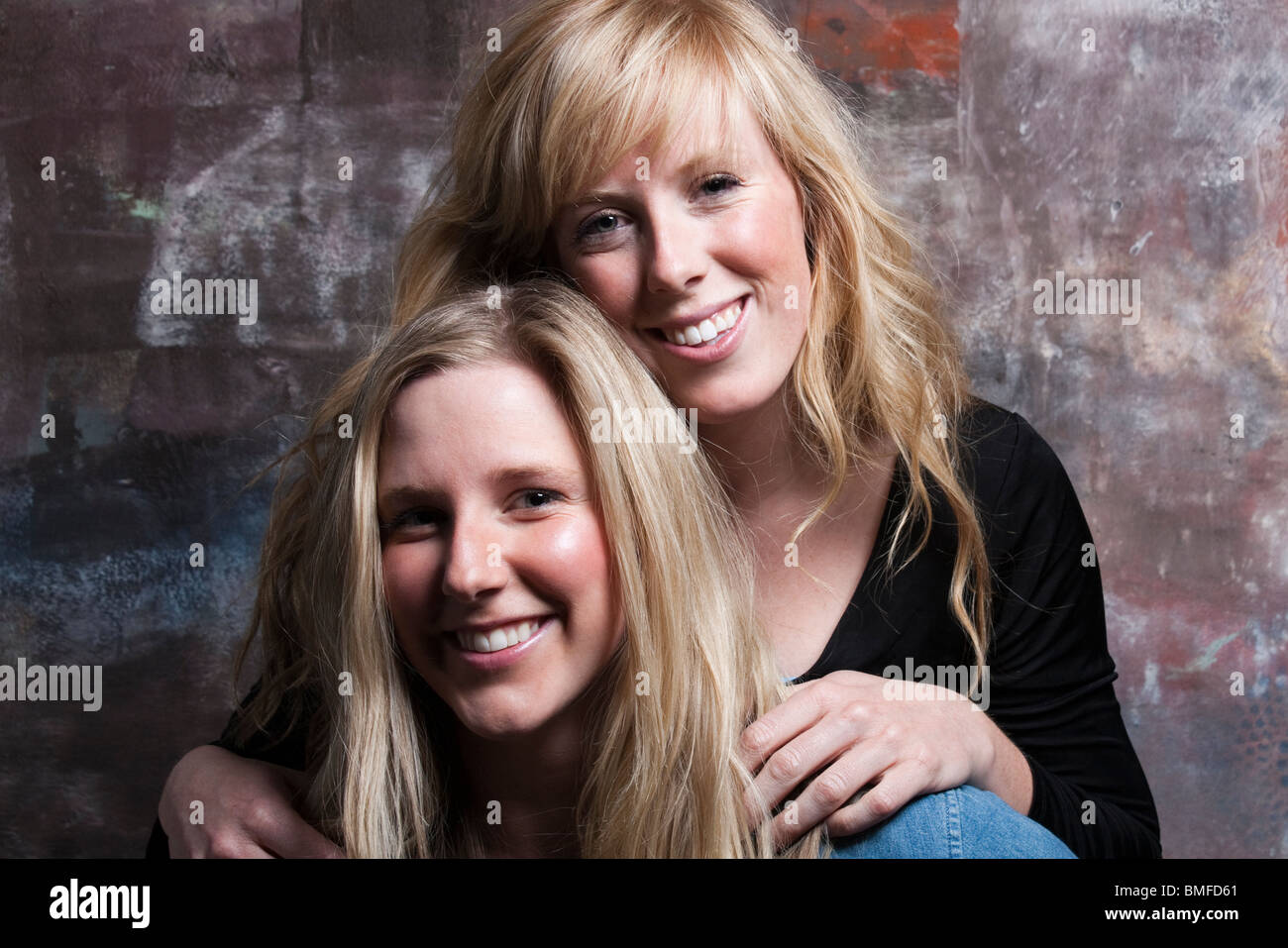 Two smiling women hugging in studio Stock Photo - Alamy