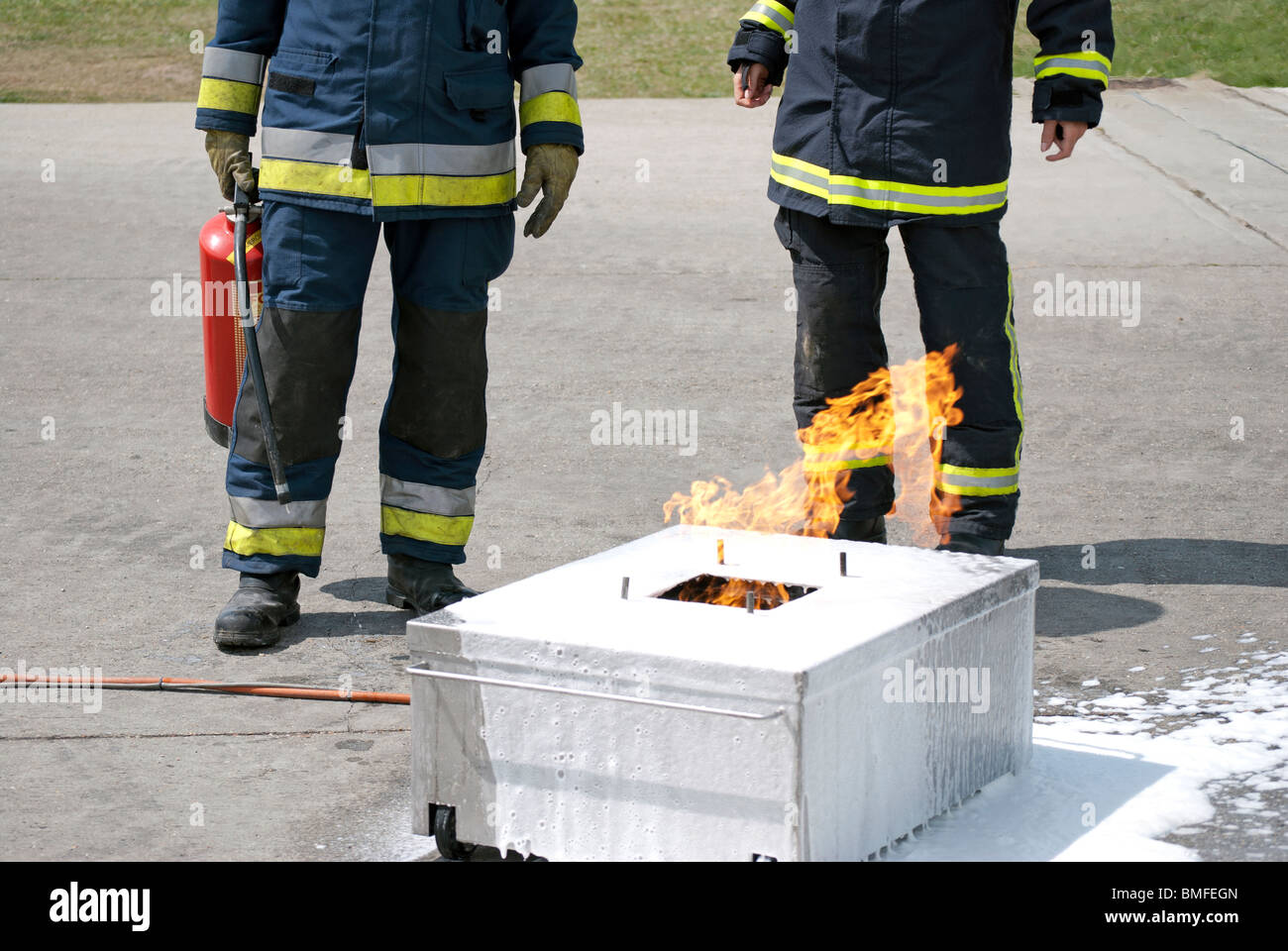 Firefighters in training putting out a controlled fire with an ...